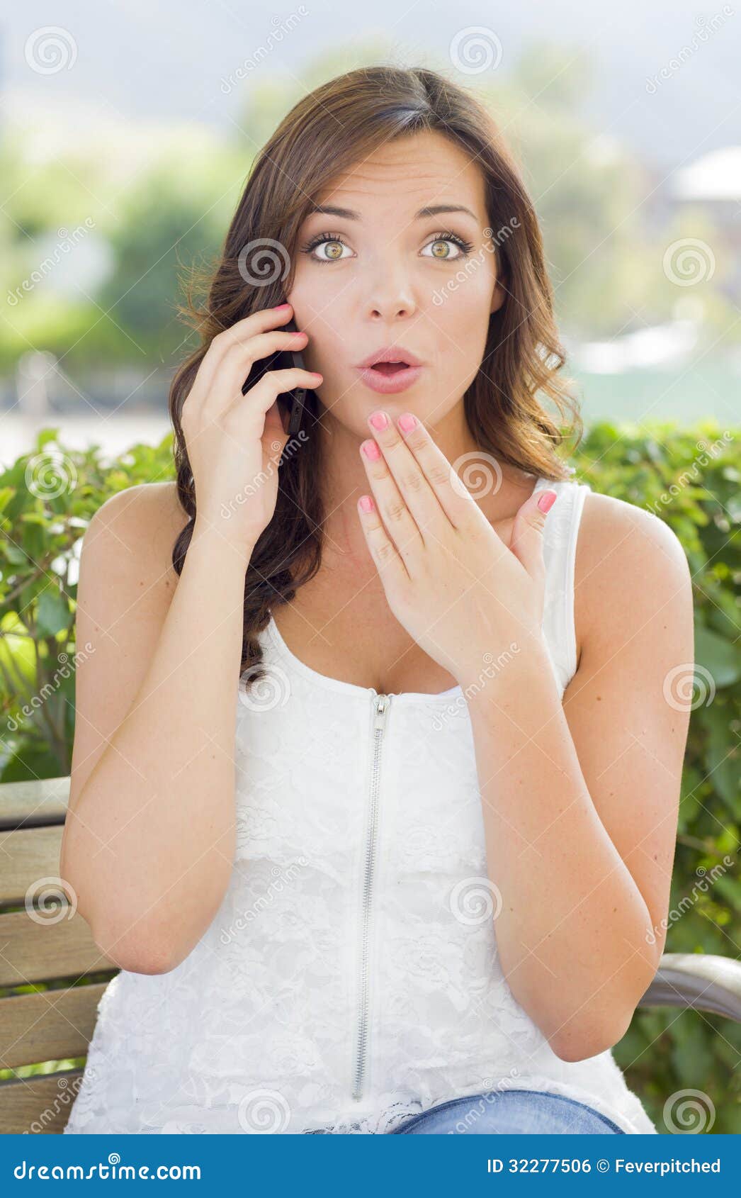 Shocked Young Adult Female Talking On Cell Phone Outdoors Royalty Free