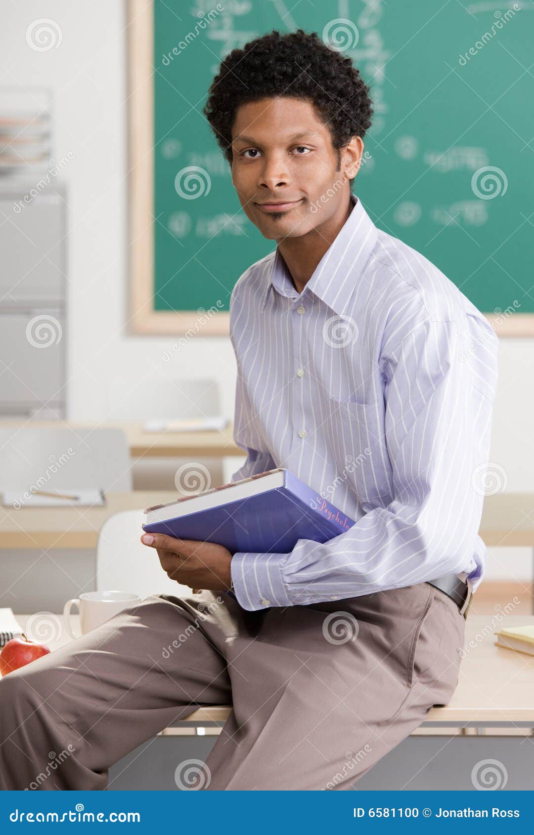Teacher Holding School Book Posing In Classroom Stock Photo - Image ... Teacher Holding School Book Posing In Classroom Stock Photo - Image ...