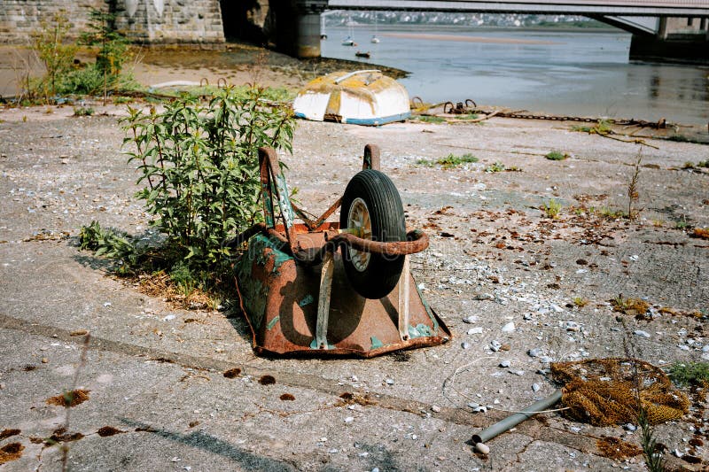 Abandoned Riverfront with Rusty Wheelbarrow and Debris, Near a ...