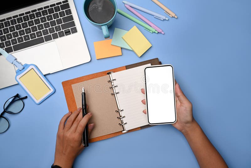 Female Employee Holding Mobile Phone and Making Note on Notebook. Stock ...