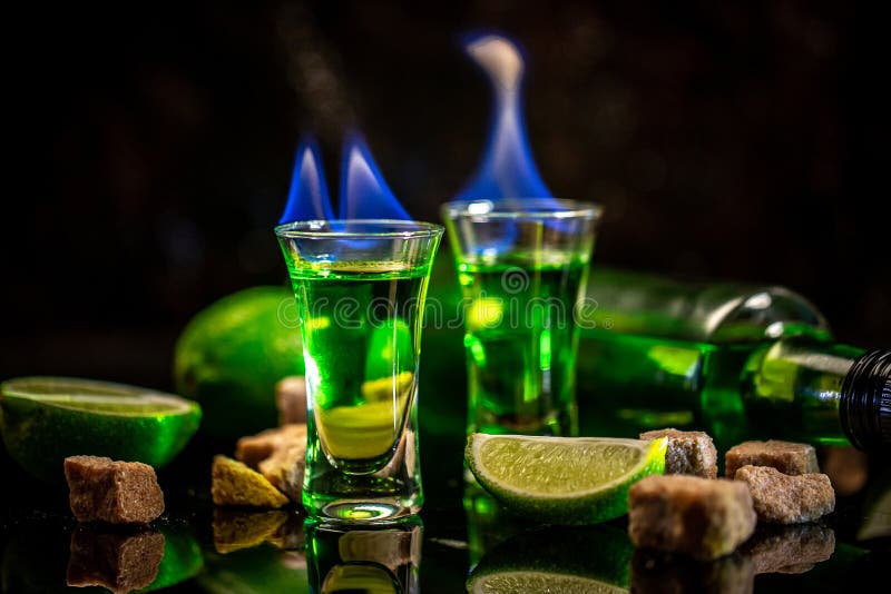 Absinthe in Glass with Lime Slices on Dark Background. Bottle of ...