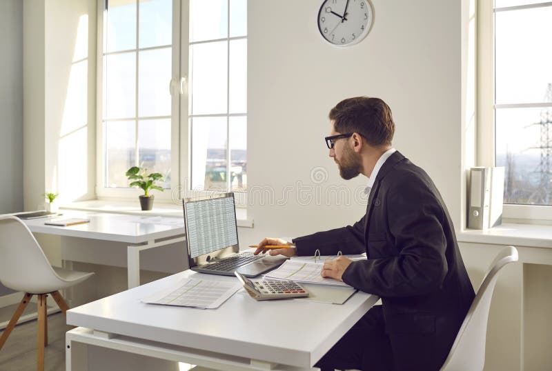 Accountant Sitting at His Office Desk and Working with Data Sheets on a ...