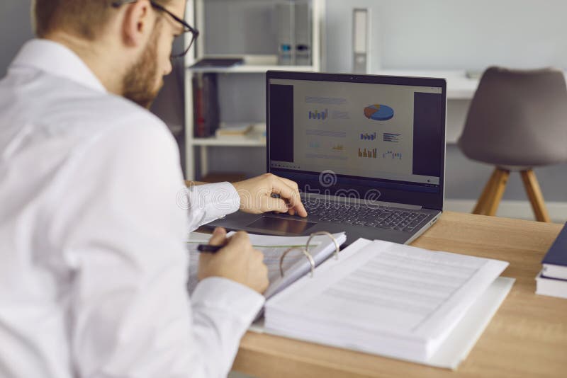 Accountant Sitting at Office Desk, Working with Budget, and Using ... Accountant Sitting at Office Desk, Working with Budget, and Using ...
