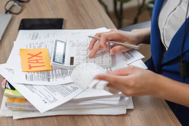 Accountant Calculating Taxes with a Calculator Amidst Paperwork and ...