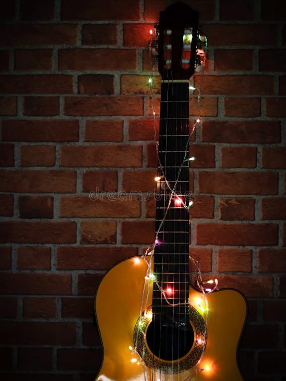 Guitar Wrapped with Glowing String Lights on Brick Wall Stock Image ...