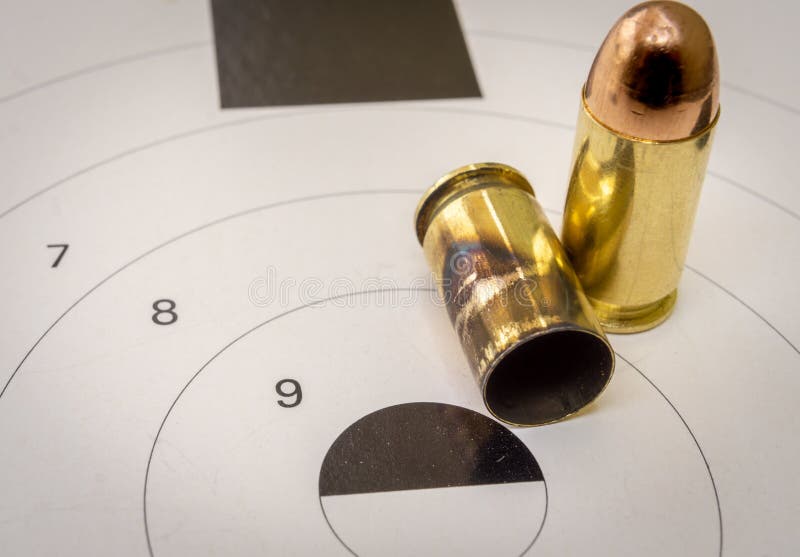 A 45 Acp Bullet with a Paper Target in the Background Stock Photo ...