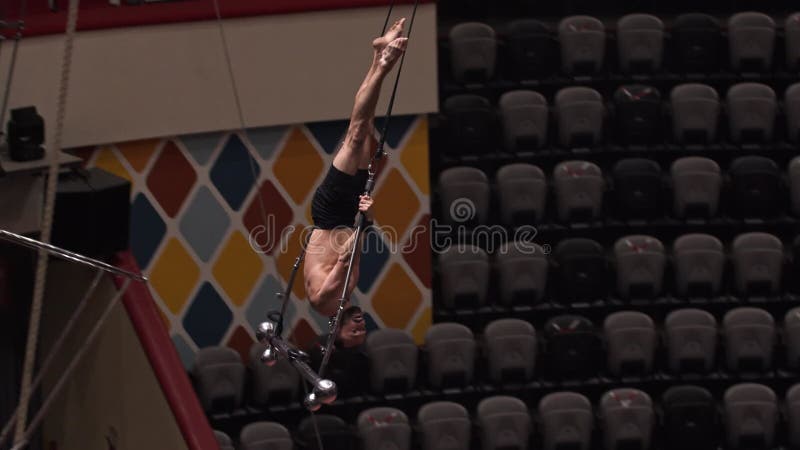 An Acrobatic Man Rotating Upside Down on the Flying Bar at Circus Stock ...