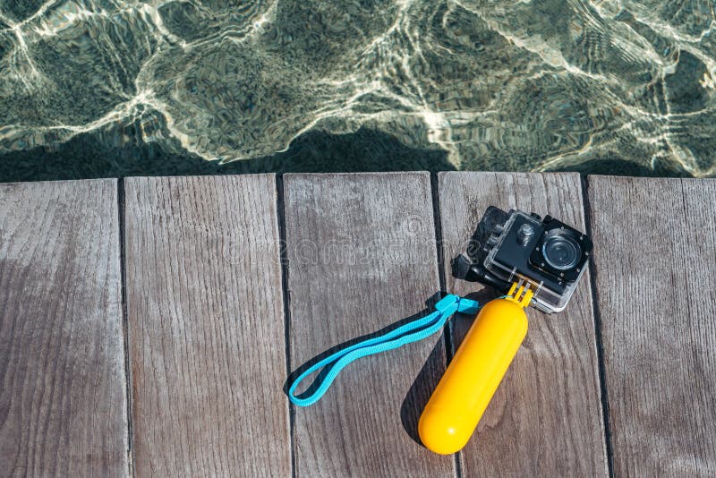 An Action Camera with a Yellow Float Lies on a Wooden Deck Against the ...