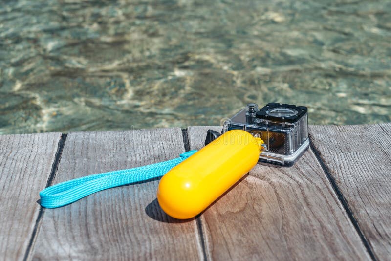 An Action Camera with a Yellow Float Lies on a Wooden Deck Against the ...