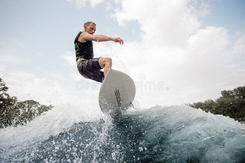 Active Man Jumping Up on the White Wakeboard on the High Wave Stock ...