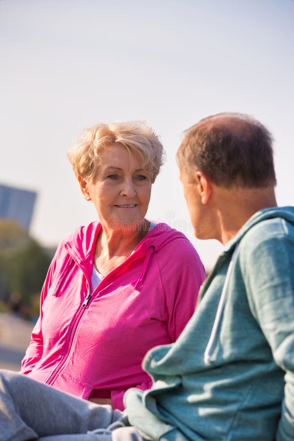 Active Senior Couple Talking while Resting on Bench at Park Stock Photo ...
