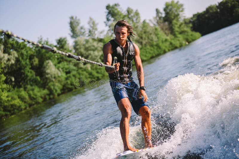 Active Wakesurfer Jumping on Wake Board Down the River Waves. Surfer on ...