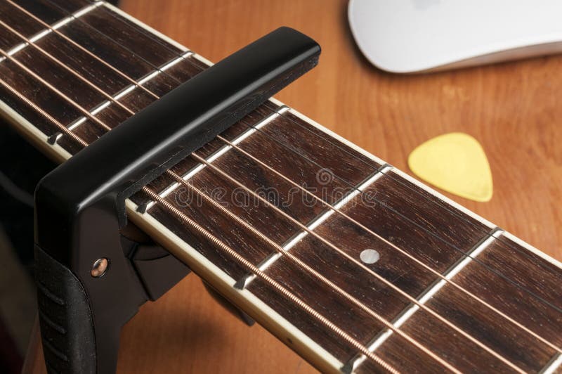 Acustic Guitar with Black Metal Capo on a Wooden Table Stock Photo ...