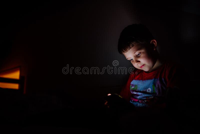 Addicted Little Boy Playing Games on Phone in Bed at Night. Stock Photo ...