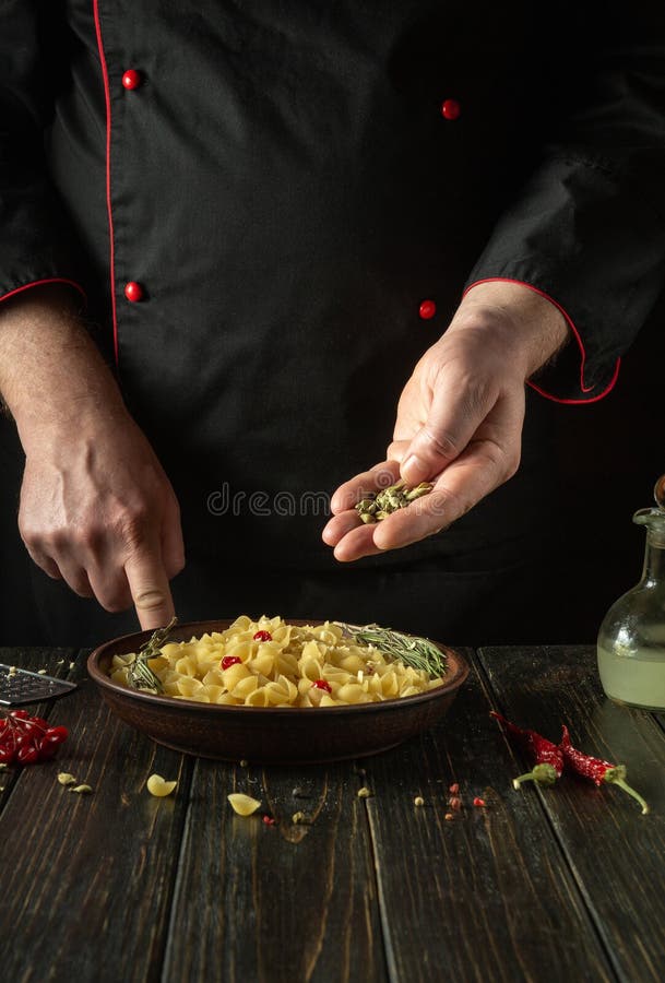 Adding Aromatic Spices To a Bowl of Pasta. the Chef at the Kitchen ...