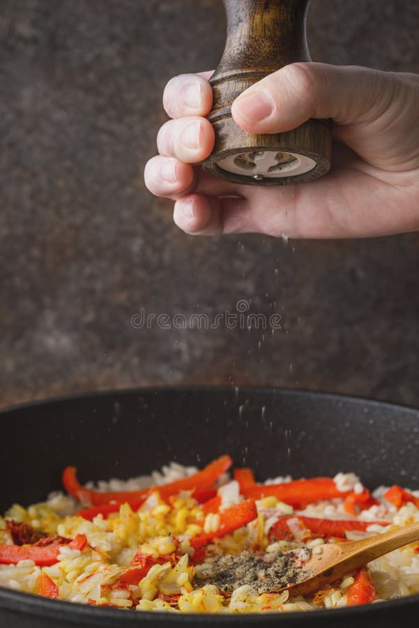 Adding Black Pepper in the Pan with Rice and Bell Pepper Vertical Stock ...
