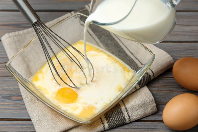 Adding Milk To Whisked Eggs at Wooden Table Stock Image - Image of ...