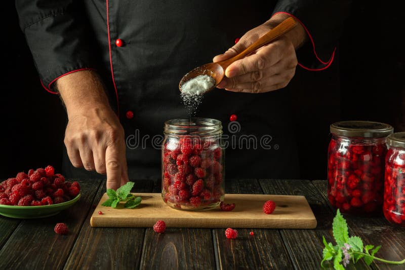 Adding Sugar with a Spoon To a Jar of Raspberries before Canning on the ...