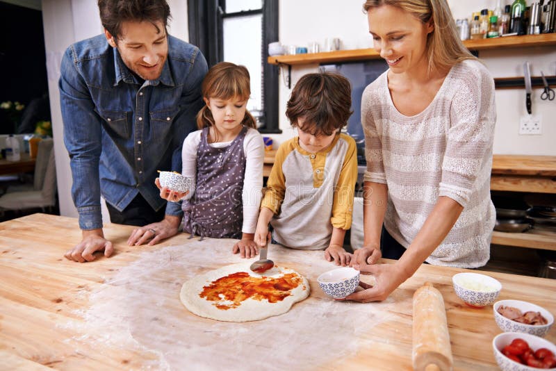 Adding the Tomato Base...a Family Making Pizza Together at Home. Stock ...