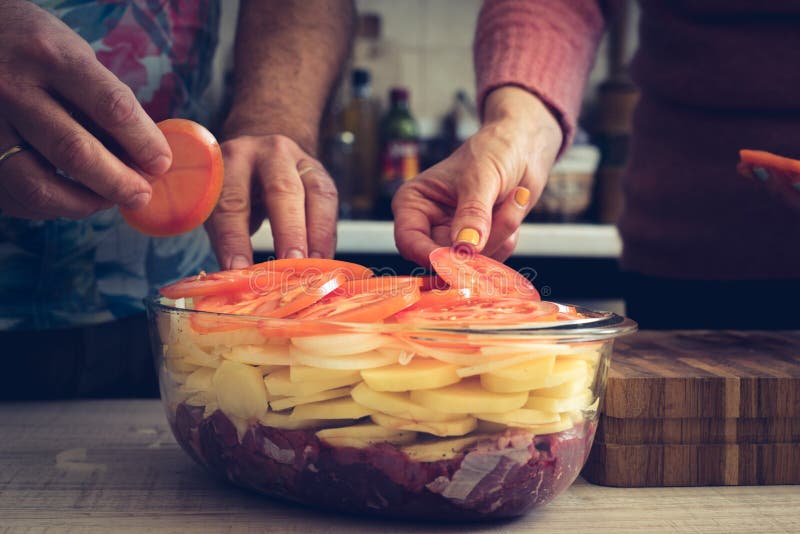 Adding Tomatoes in the Baking Dish with Raw Meat and Potatoes Stock ...