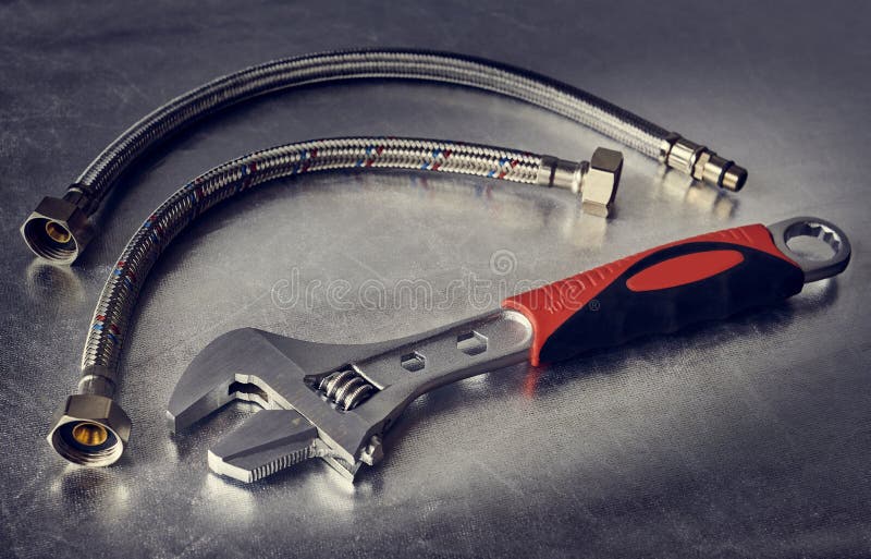 Adjustable Wrench and Flexible Connecting Hoses on Silver Surface Stock ... Adjustable Wrench and Flexible Connecting Hoses on Silver Surface Stock ...