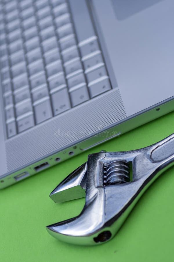 Adjustable Wrench Next To a Silver Laptop. Computer Service ...