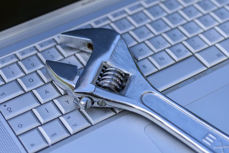 Adjustable Wrench Next To a Silver Laptop. Computer Service ...