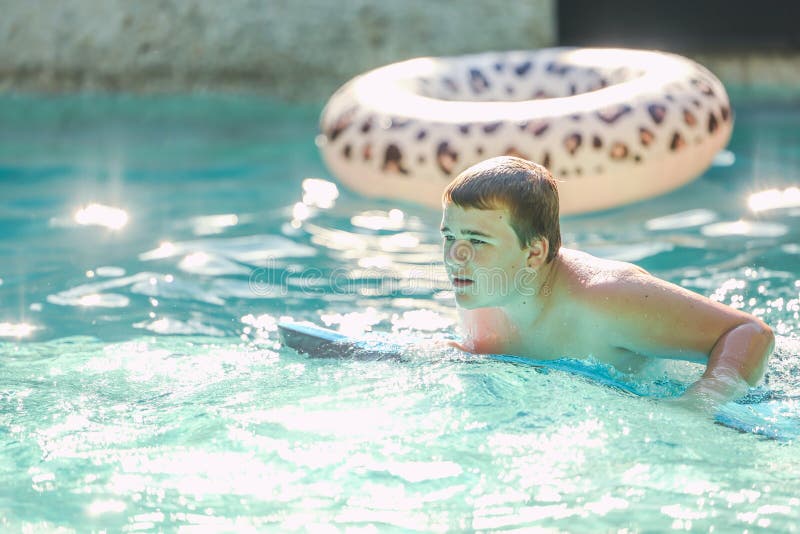 Adolescent Boy Swimming on Boogie Board in Backyard Pool in the Summer ...