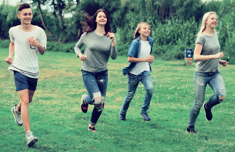 Adolescents Courant Dans La Pelouse Verte En été Dans Le Parc Image