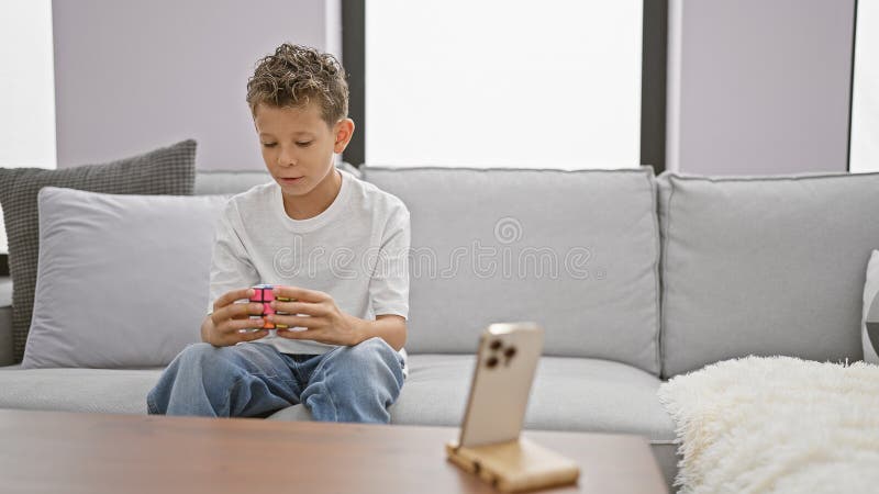 Adorable Blond Boy Sitting on Sofa, Confidently Solving Rubik Cube ...