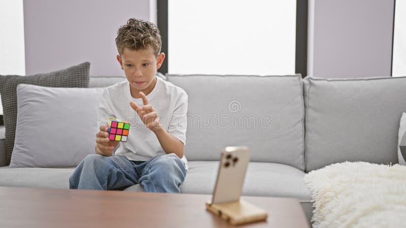 Adorable Blond Boy Sitting on Sofa, Confidently Solving Rubik Cube ...