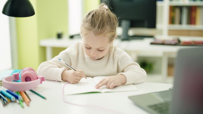 Adorable Blonde Girl Student Drawing on Notebook Sitting on Table at ...