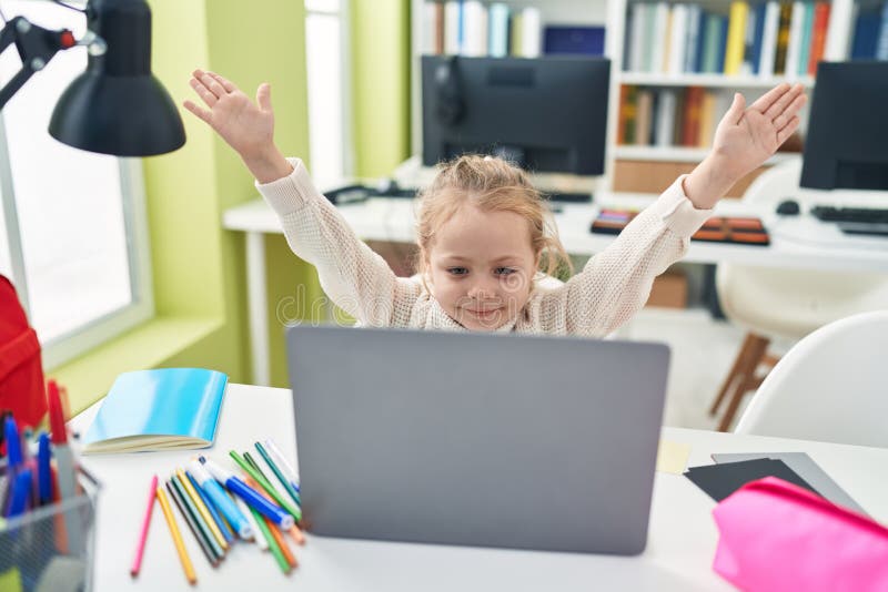 Adorable Blonde Girl Student Using Laptop with Cheerful Expression at ...