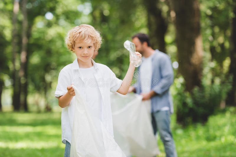 Boy with Plastic Bag Picking Up Garbage with Father in Park Stock Photo ...
