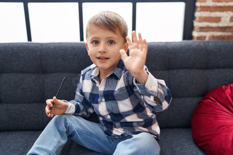 Adorable Caucasian Boy Saying Hello with Hand Sitting on Sofa at Home ...