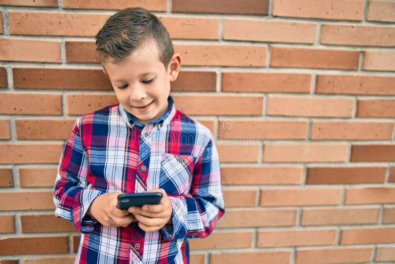 Adorable Caucasian Boy Smiling Happy Using Smartphone at the City Stock ...