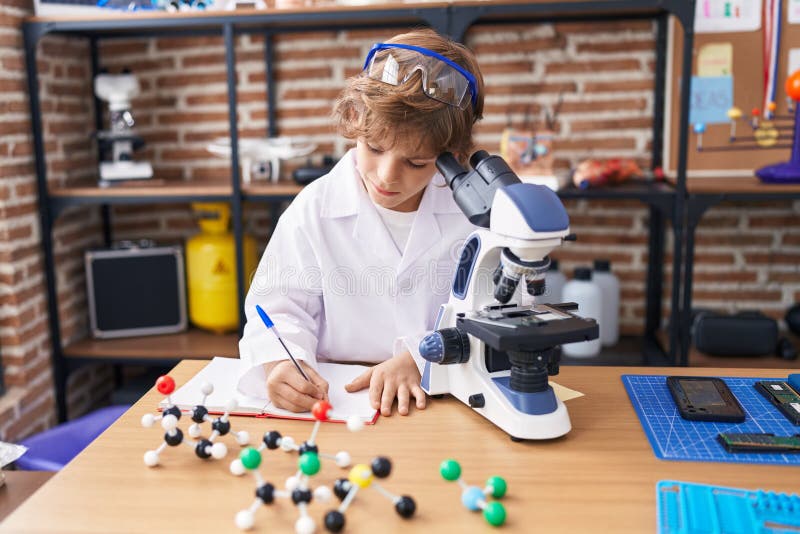 Adorable Caucasian Boy Student Using Microscope Writing on Notebook at ...