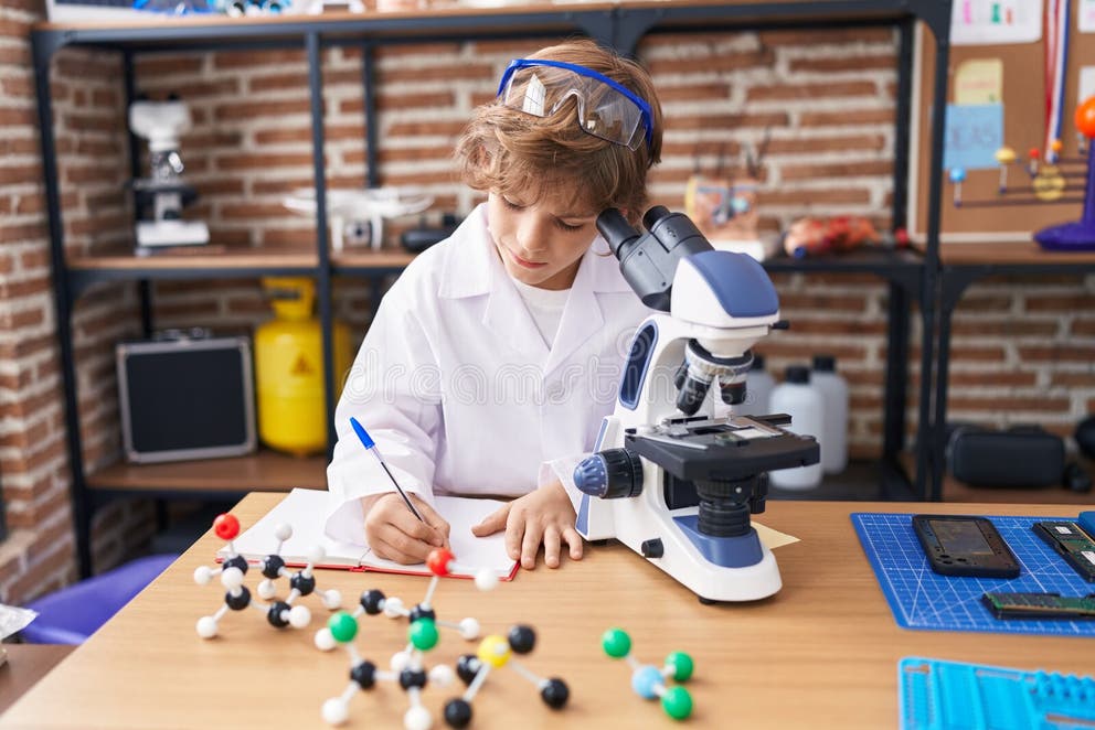 Adorable Caucasian Boy Student Using Microscope Writing on Notebook at ...