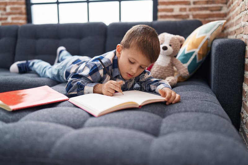 Adorable Caucasian Boy Student Writing on Notebook Lying on Sofa at ...