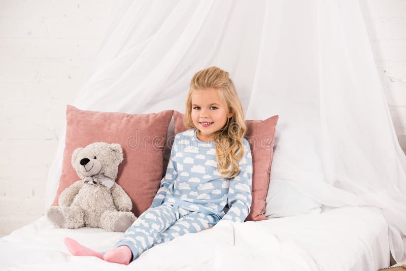 Adorable Child Sitting on Bed Stock Image - Image of pillows, indoors ...