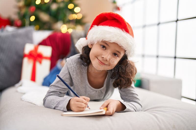 Adorable Chinese Girl Writing on Notebook Lying on Sofa by Christmas ...