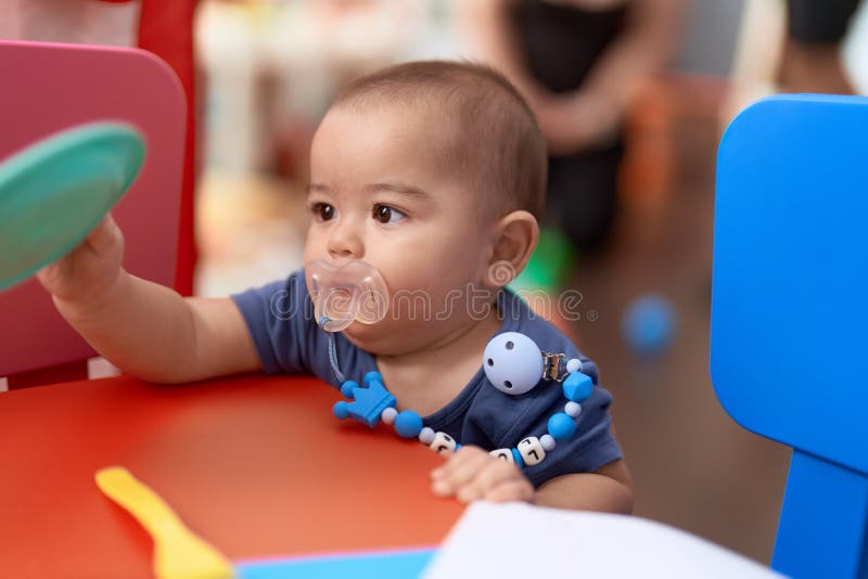 Adorable Chinese Toddler Using Pacifier Holding Dish Toy at ...