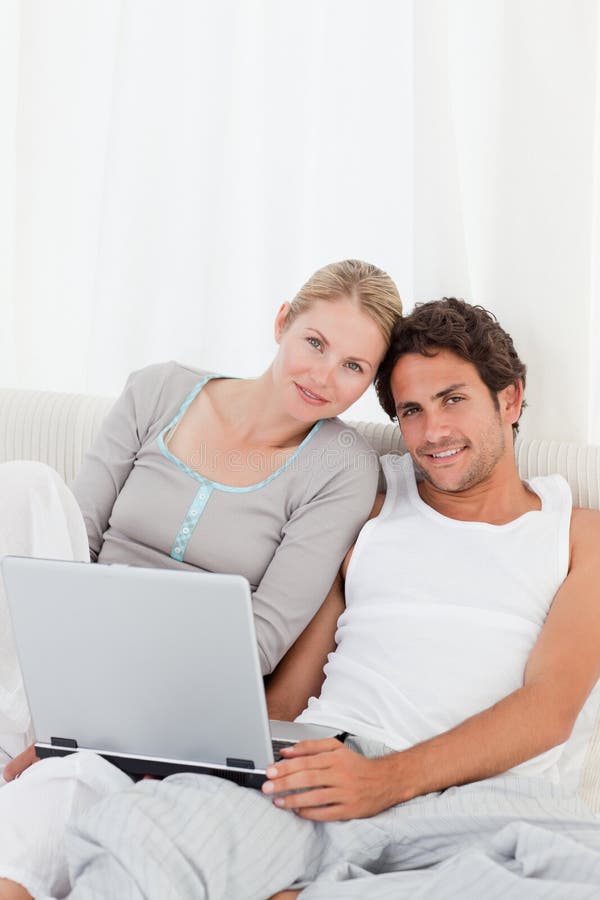 Adorable Couple Looking at Their Laptop on the Bed Stock Photo - Image ...