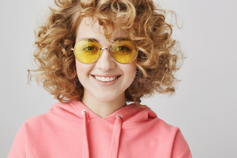 Adorable Curly Haired Woman With Fashionable Yellow Sunglasses Smiling