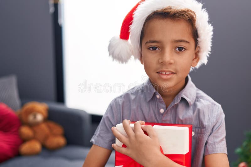 Adorable Hispanic Boy Hugging Christmas Gift Standing at Home Stock ...