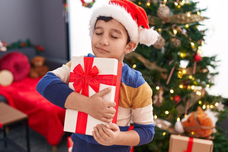 Adorable Hispanic Boy Hugging Christmas Gift Standing at Home Stock ...