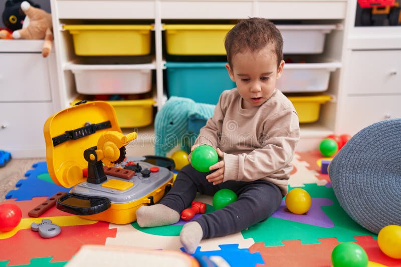 Adorable Hispanic Boy Playing with Balls Sitting on Floor at ...