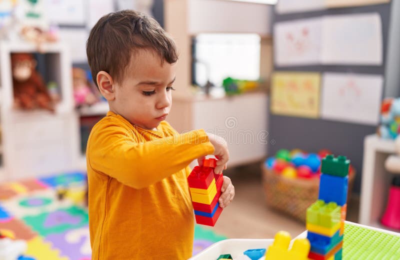 Adorable Hispanic Boy Playing with Construction Blocks Standing at ...