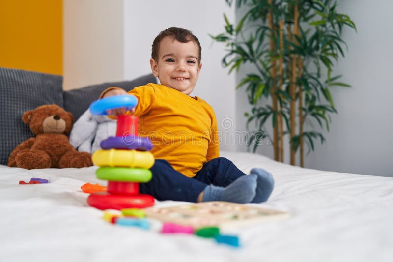 Adorable Hispanic Boy Playing with Hoops Game Sitting on Bed at Bedroom ...