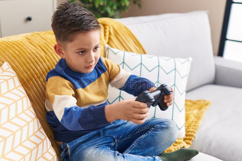 Adorable Hispanic Boy Playing Video Game Sitting on Sofa at Home Stock ...